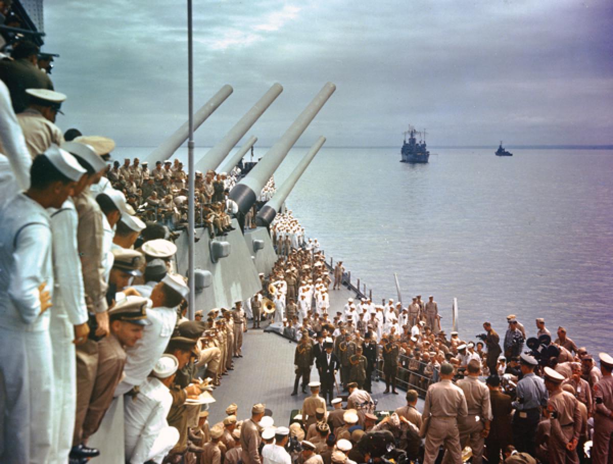 Civilians look at a turret salvaged from the wreck of the battleship ...